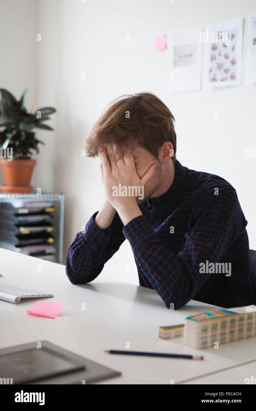 Overworked businessman with hands on face at desk Stock Photo - Alamy