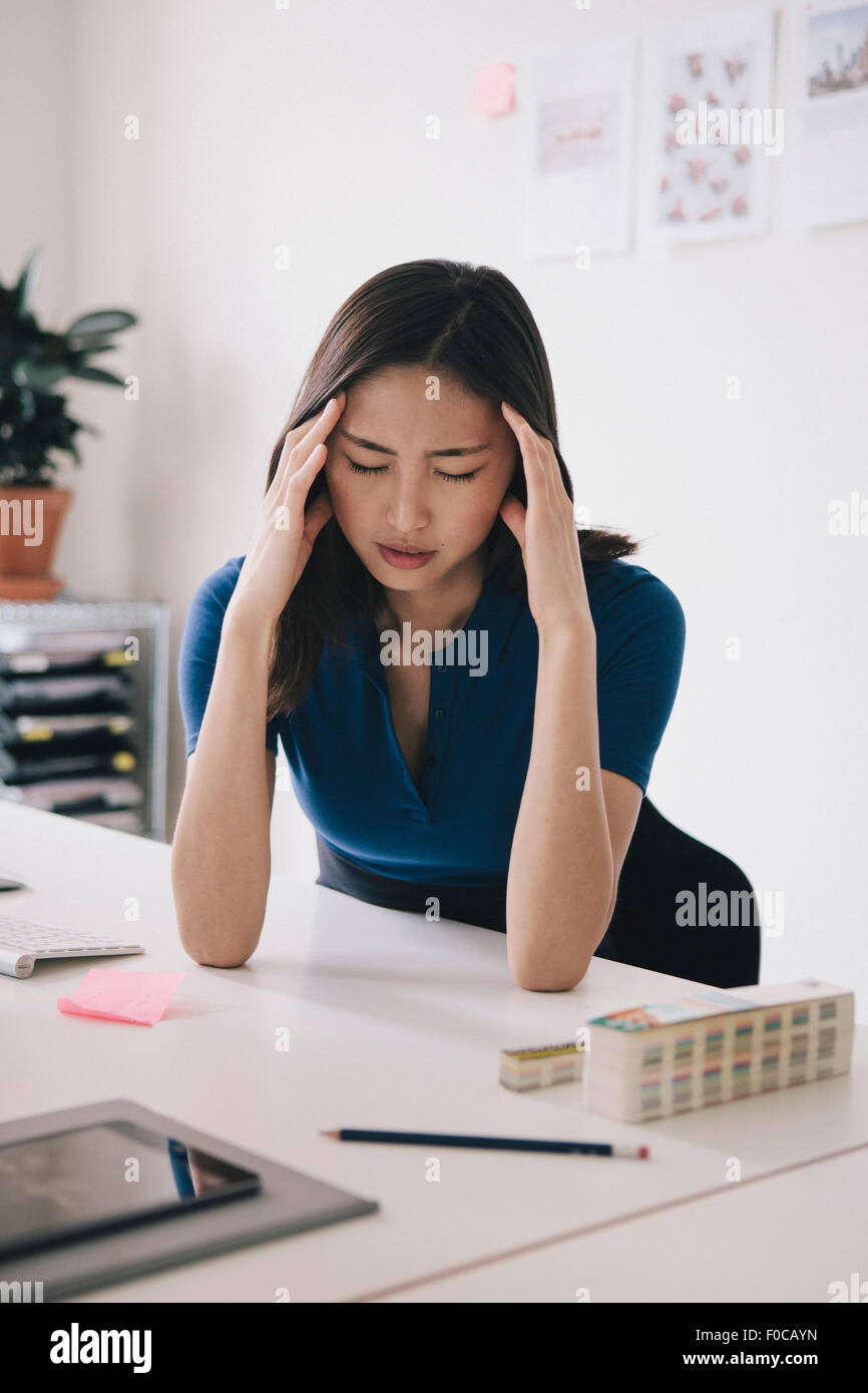 Young businesswoman suffering from headache at desk Stock Photo - Alamy