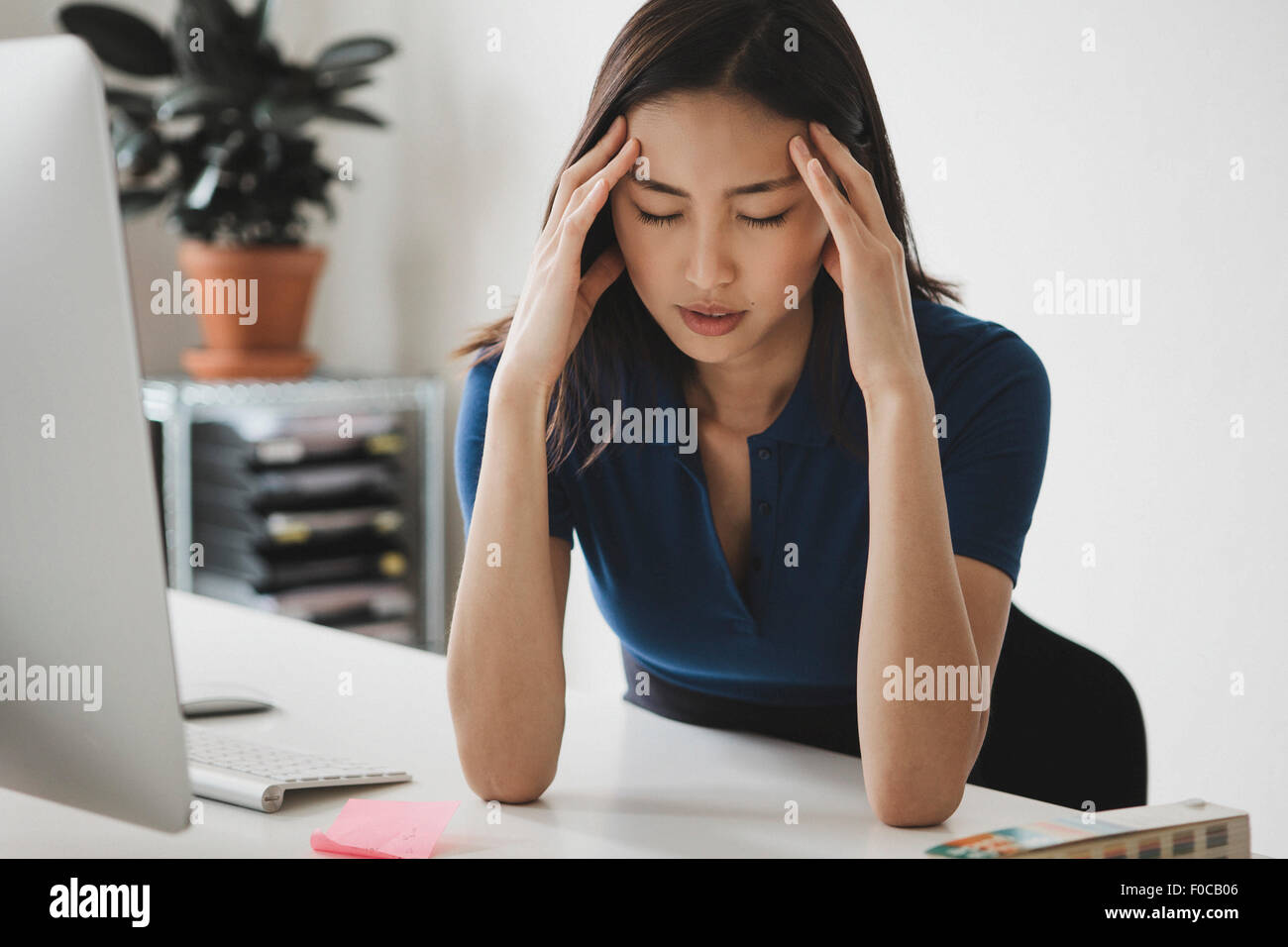Young businesswoman suffering from headache at desk in office Stock ...
