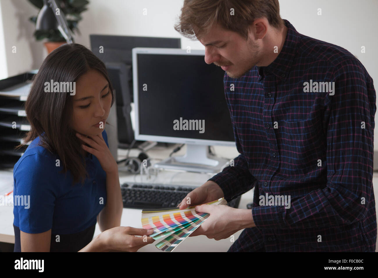 Young male and female business colleagues choosing color from swatches ...