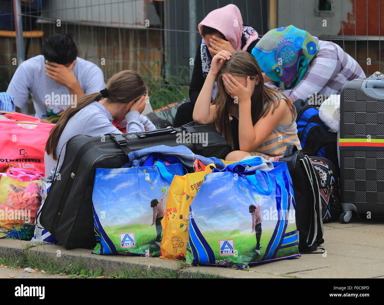 Refugees sit in front of the central reception centre for asylum ...