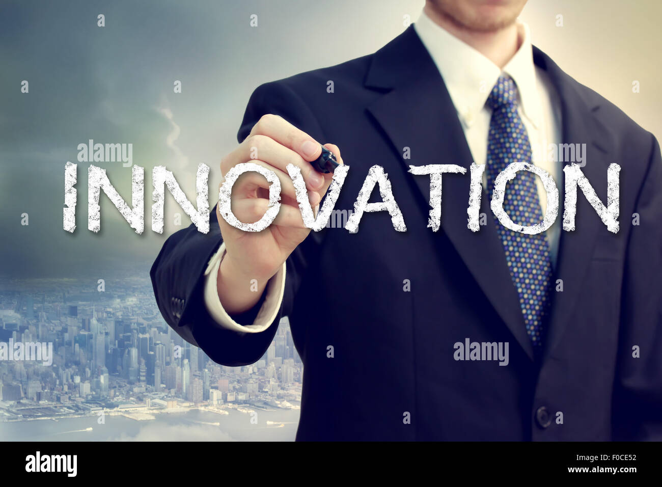 Business man drawing INNOVATION over skyline background Stock Photo - Alamy
