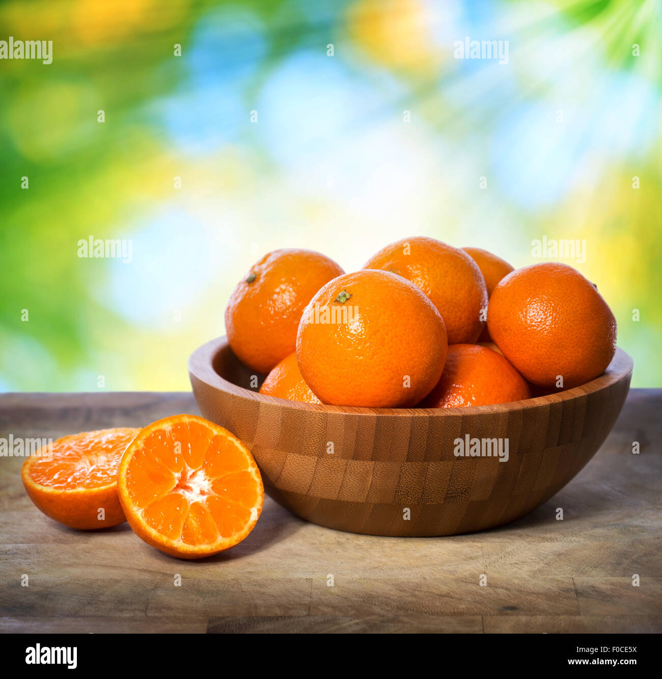 Tangerines in wooden bowl over shiny leaves background Stock Photo - Alamy