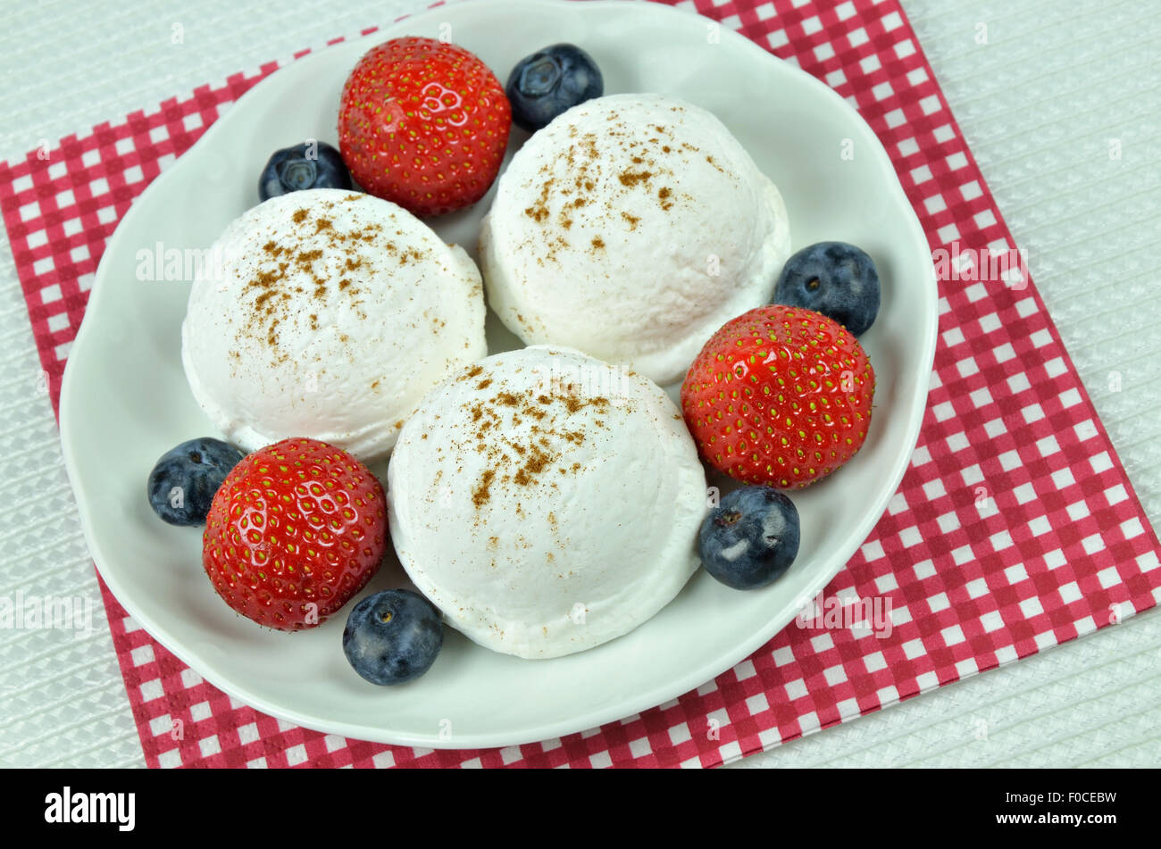 close up of a white plate with vanilla ice cream, strawberries and ...