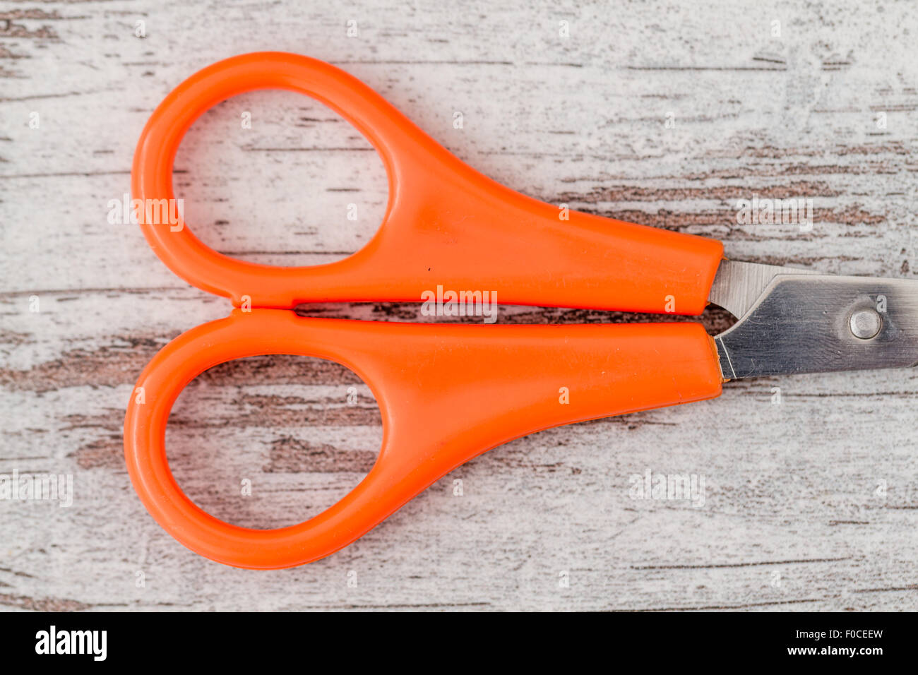 Orange metallic scissors on white wooden table background Stock Photo ...