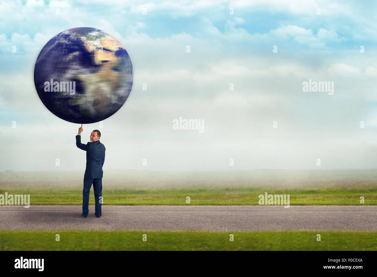 businessman holding spinning planet earth globe aloft with one finger ...