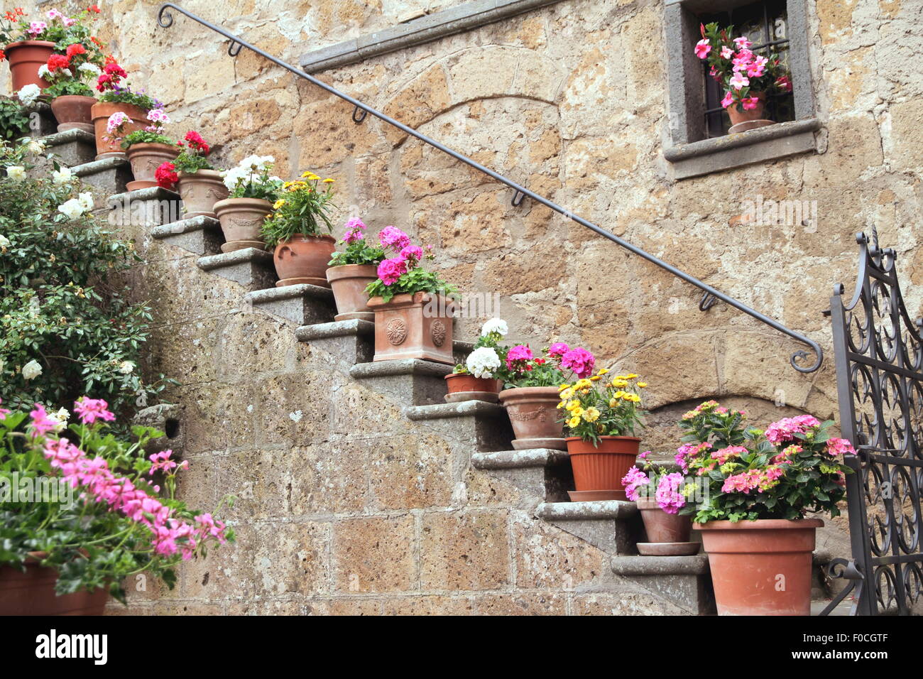 Medieval building exterior with ornamental flowers in vases in Italy ...