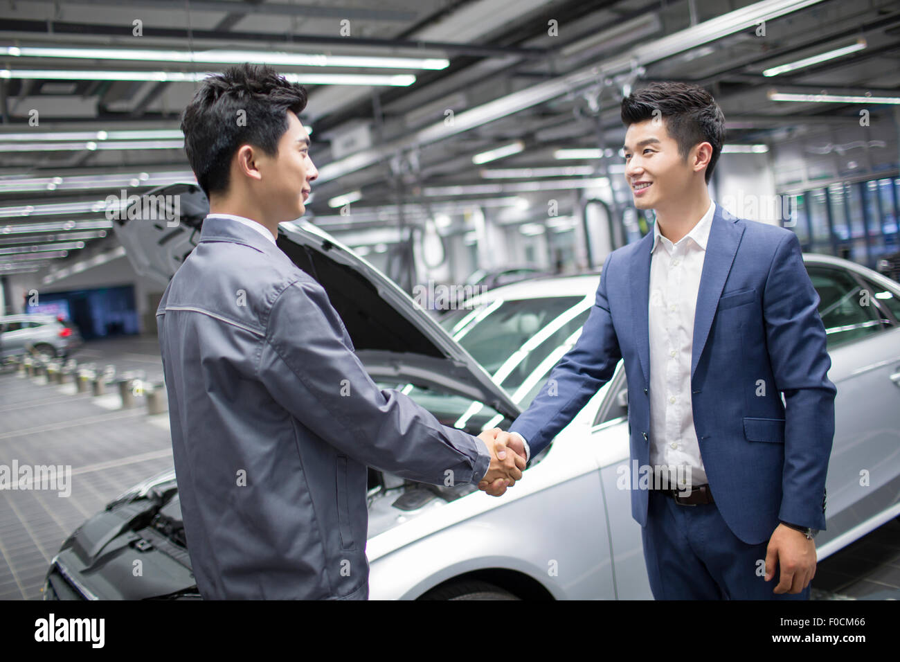 Auto mechanic and car owner shaking hands Stock Photo - Alamy