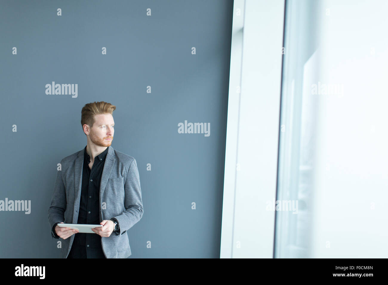 Young man with tablet by the wall Stock Photo - Alamy