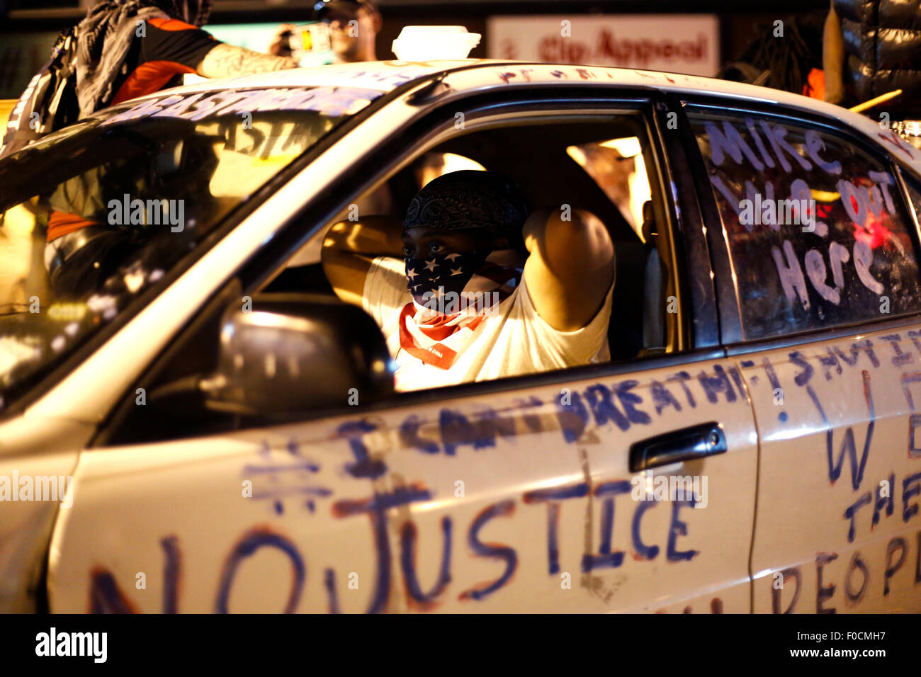 Ferguson, USA. 11th Aug, 2015. A protester covers his face with an ...