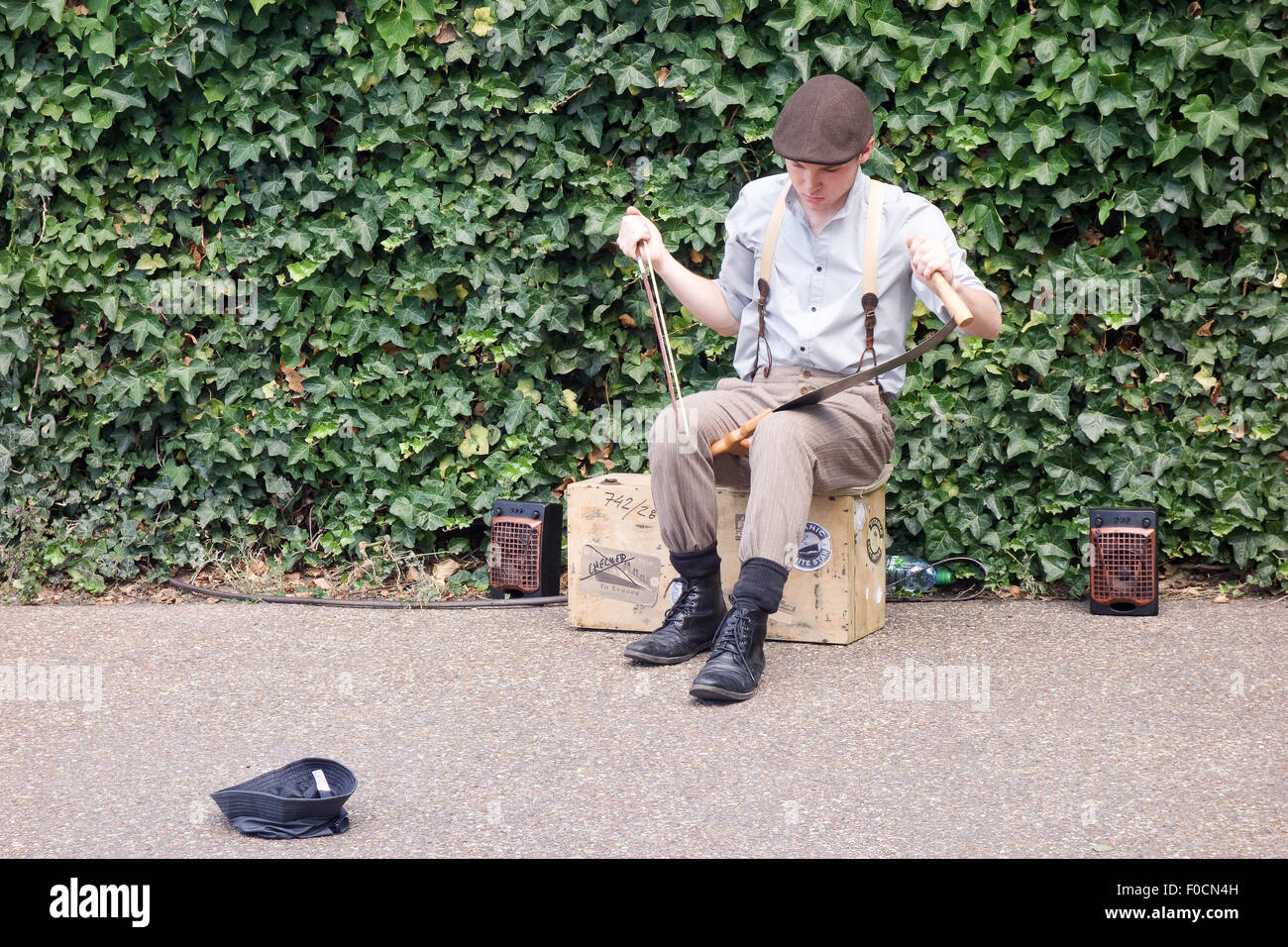 A young man busking with a unique bow instrument and dressed with ...