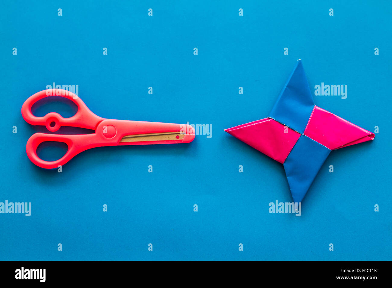 Pink toy scissors and origami star on blue paper background Stock Photo ...