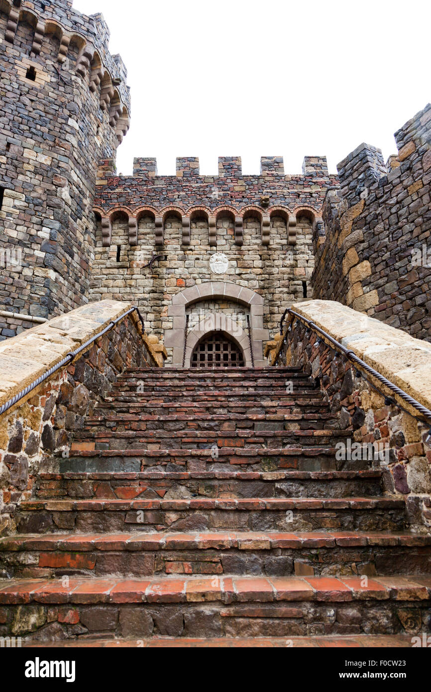 Rock and brick steps leading up to a castle entrance surrounded by tall ...