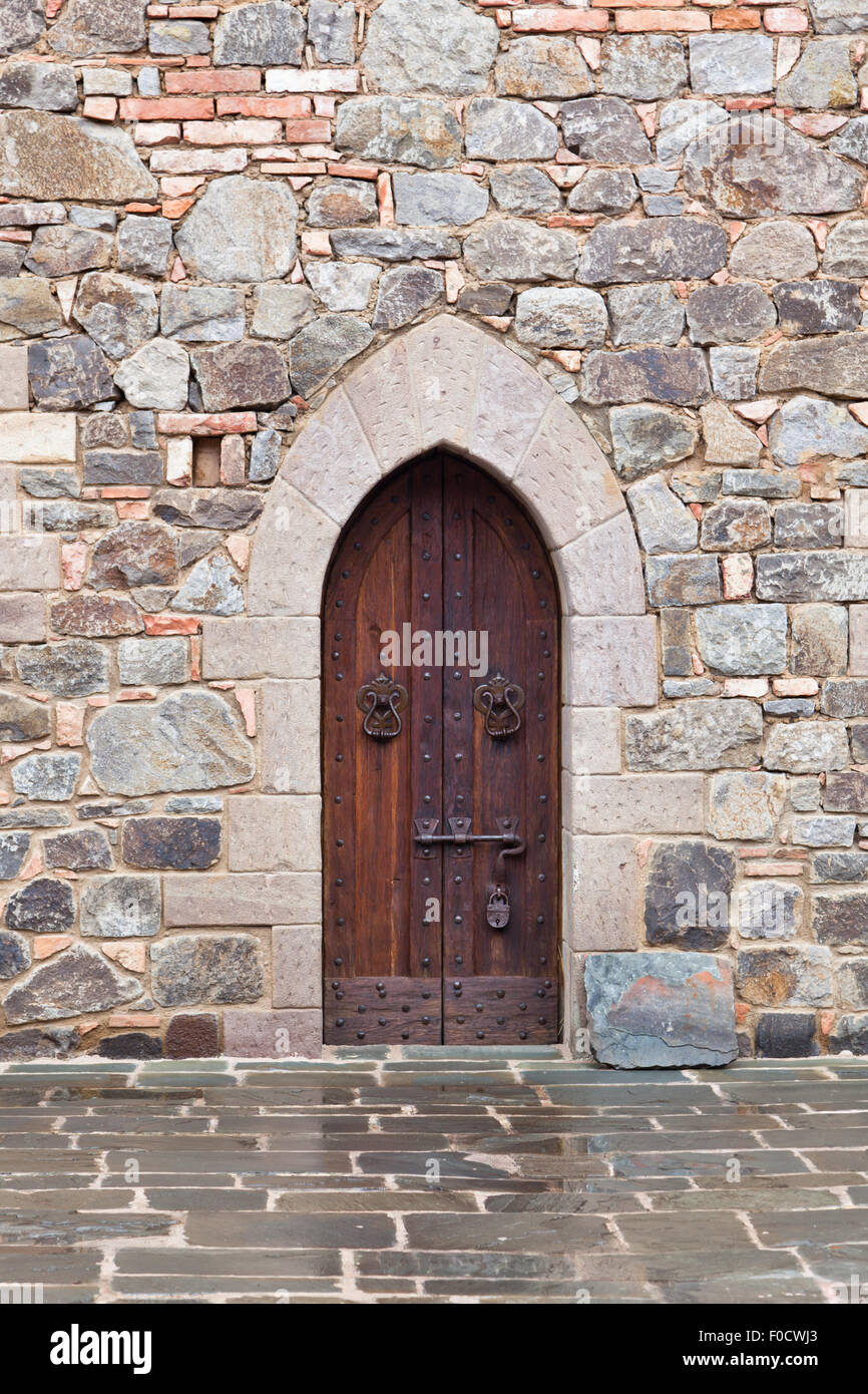 A medieval wooden door with metal accents and a metal lock framed by ...