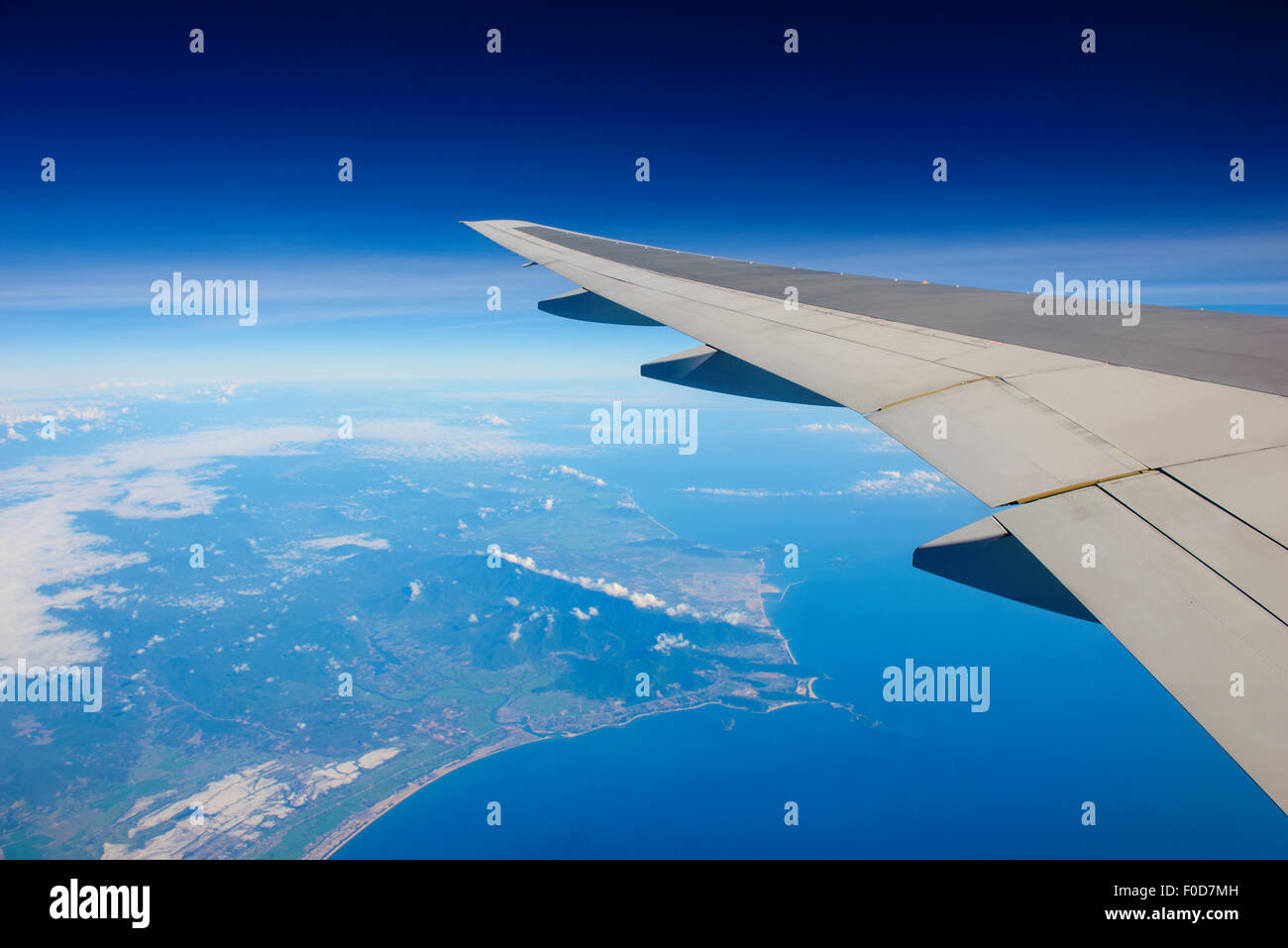 Airplane flying over ocean and island Stock Photo - Alamy