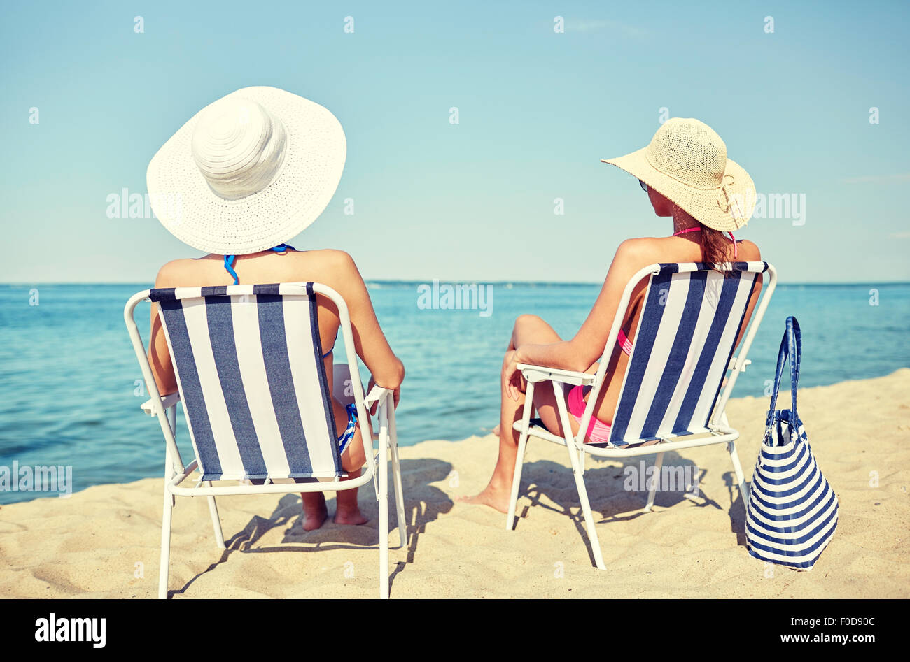 happy women sunbathing in lounges on beach Stock Photo - Alamy