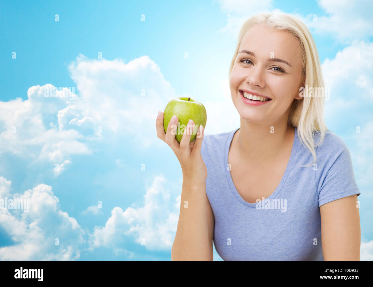 happy woman eating green apple over sky Stock Photo - Alamy