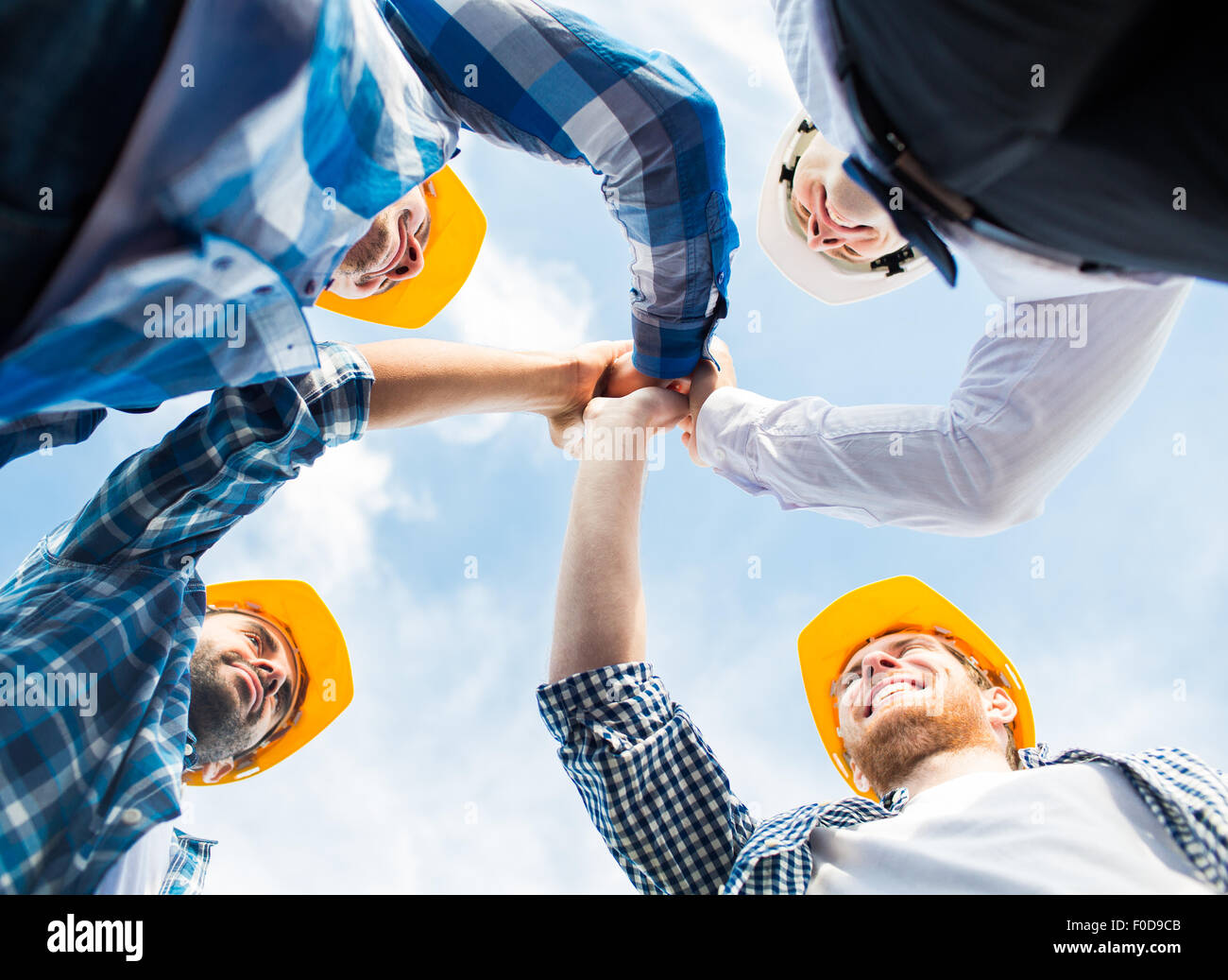 close up of builders in hardhats making high five Stock Photo - Alamy