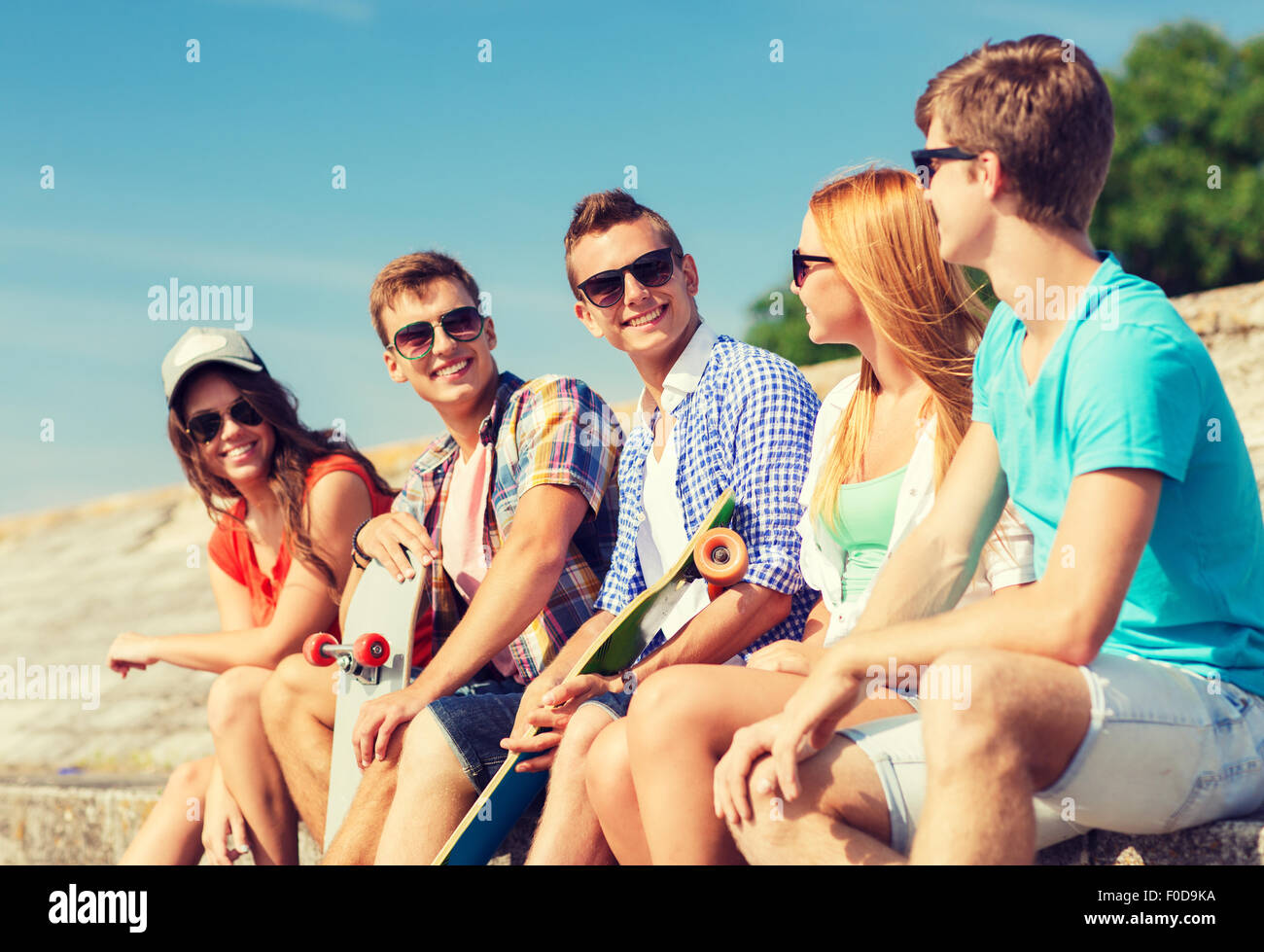 group of smiling friends sitting on city street Stock Photo - Alamy