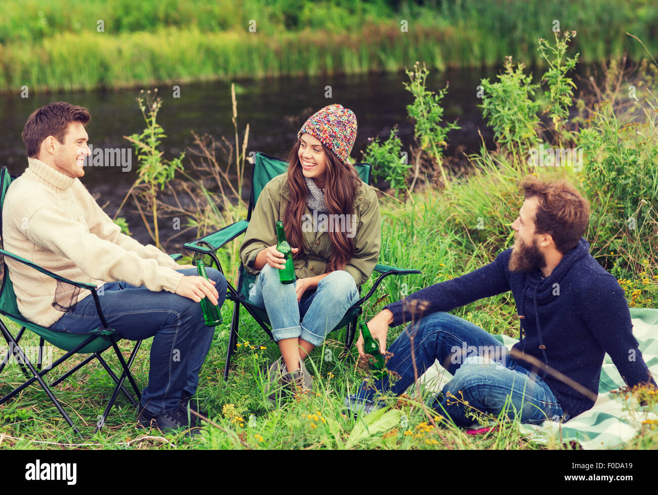 group of smiling tourists drinking beer in camping Stock Photo - Alamy