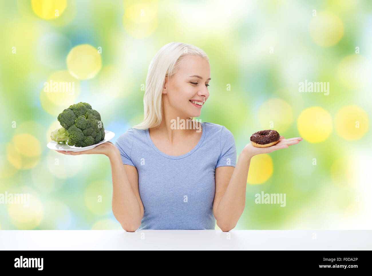 smiling woman with broccoli and donut Stock Photo - Alamy