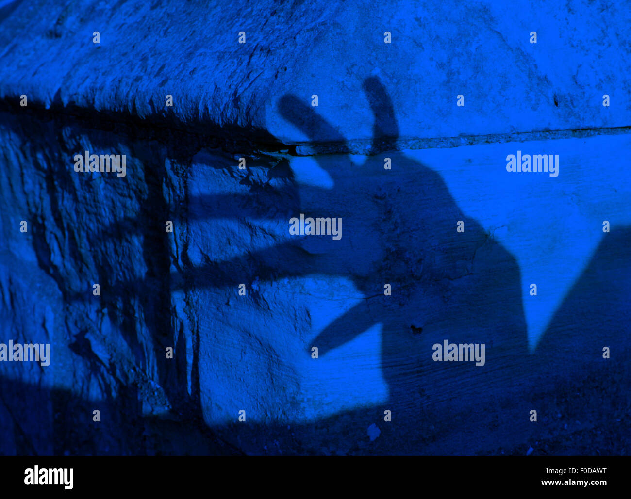Spooky hand shadow on stone wall in blue light Stock Photo - Alamy