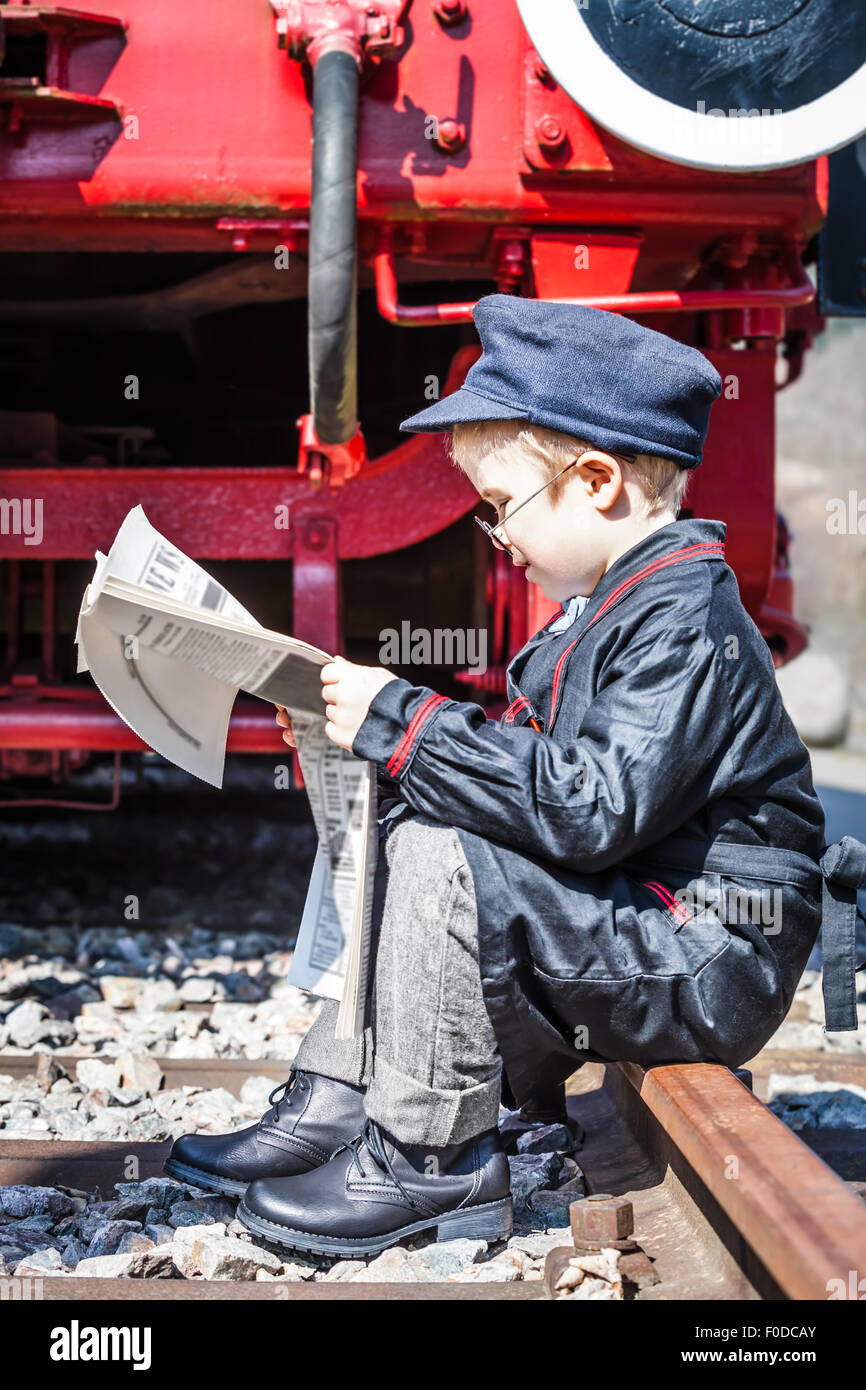 Small child boy as nostalgic locomotive driver sitting at the railway ...