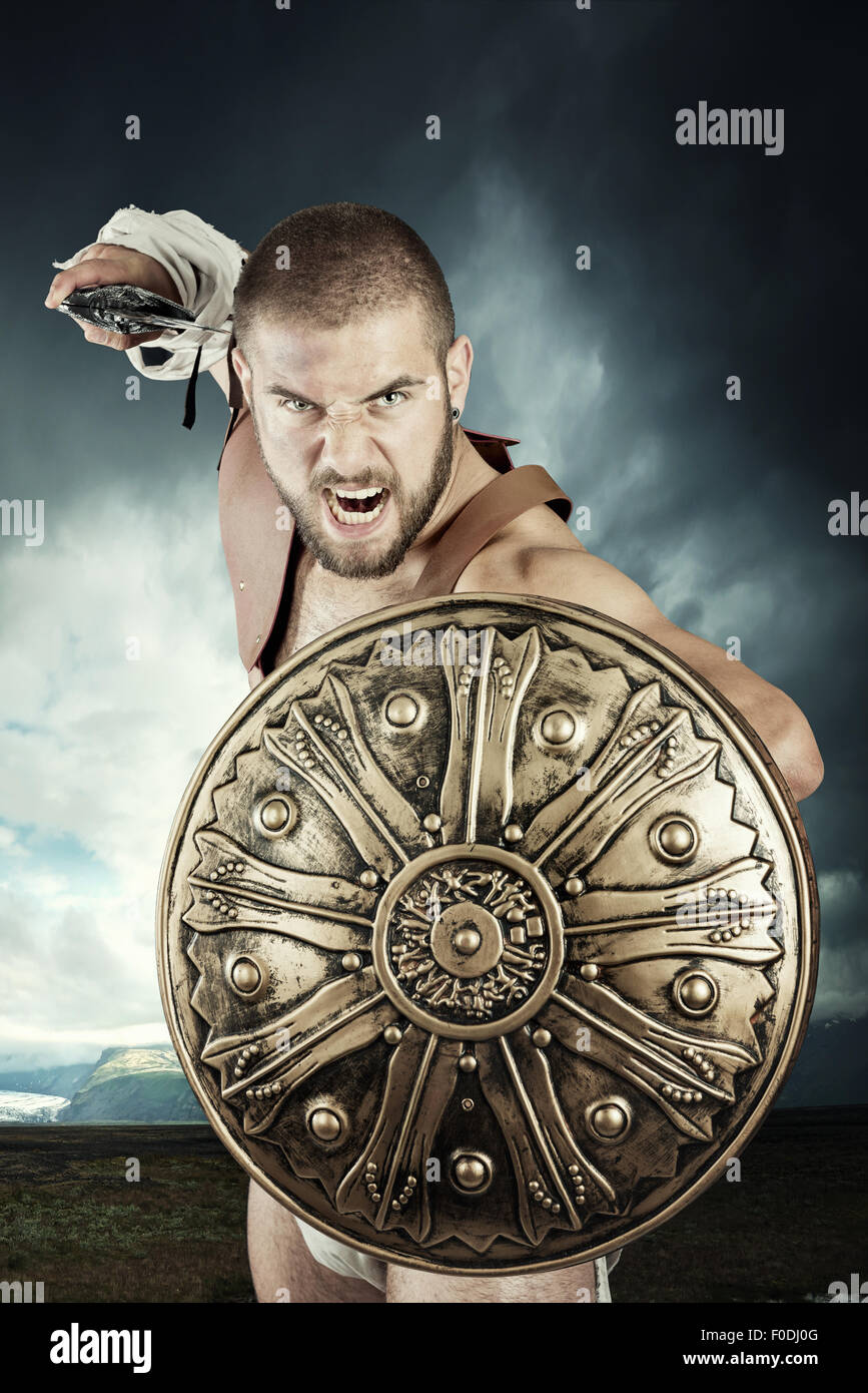 Gladiator or warrior posing with shield and sword outdoors ready for ...