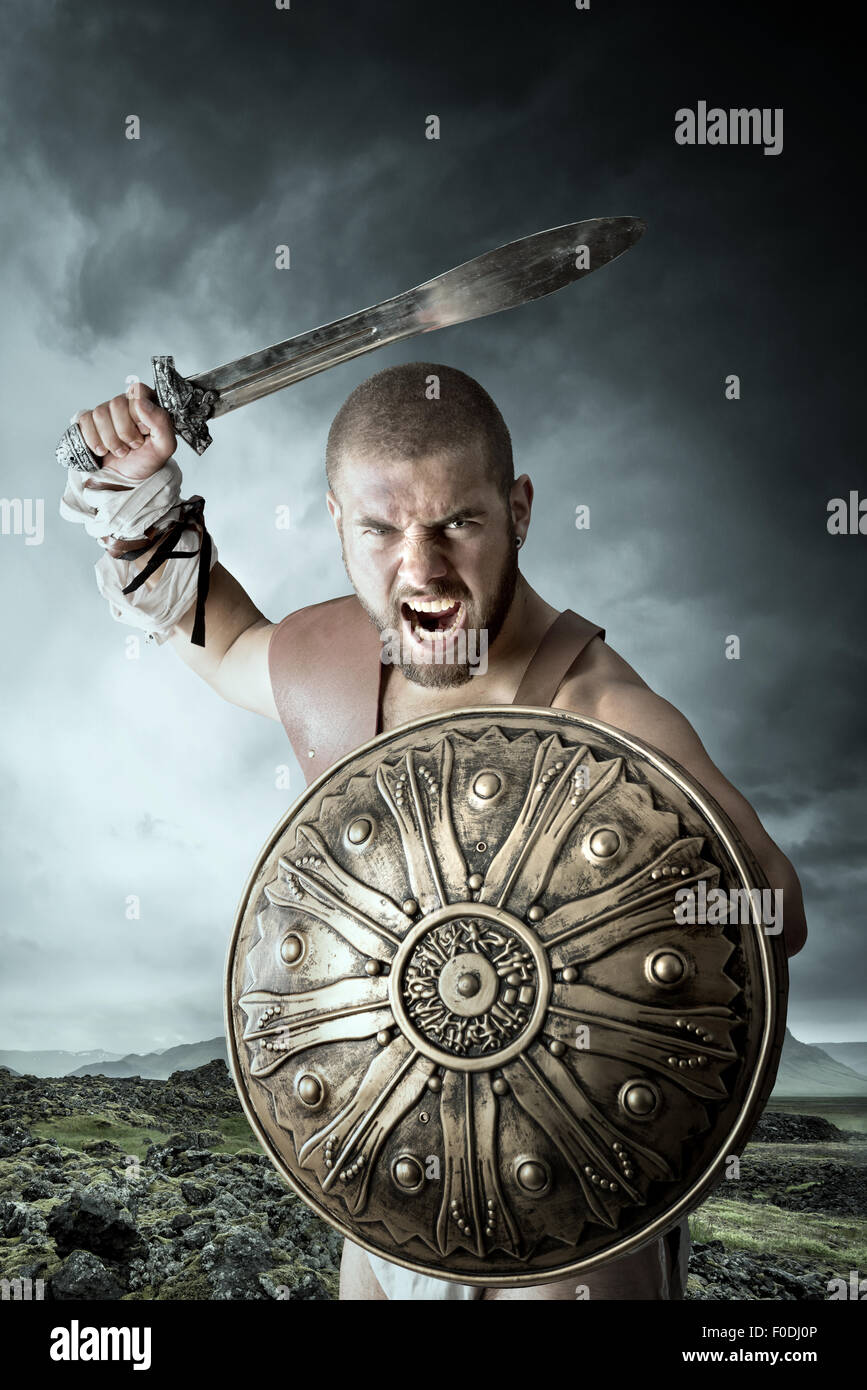 Gladiator or warrior posing with shield and sword outdoors ready for ...