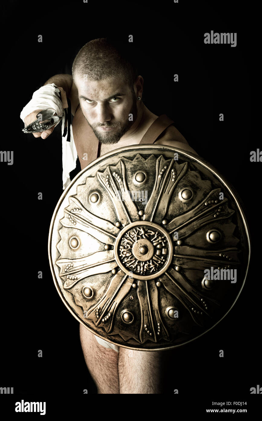 Gladiator posing with shield and sword in a dark background Stock Photo ...