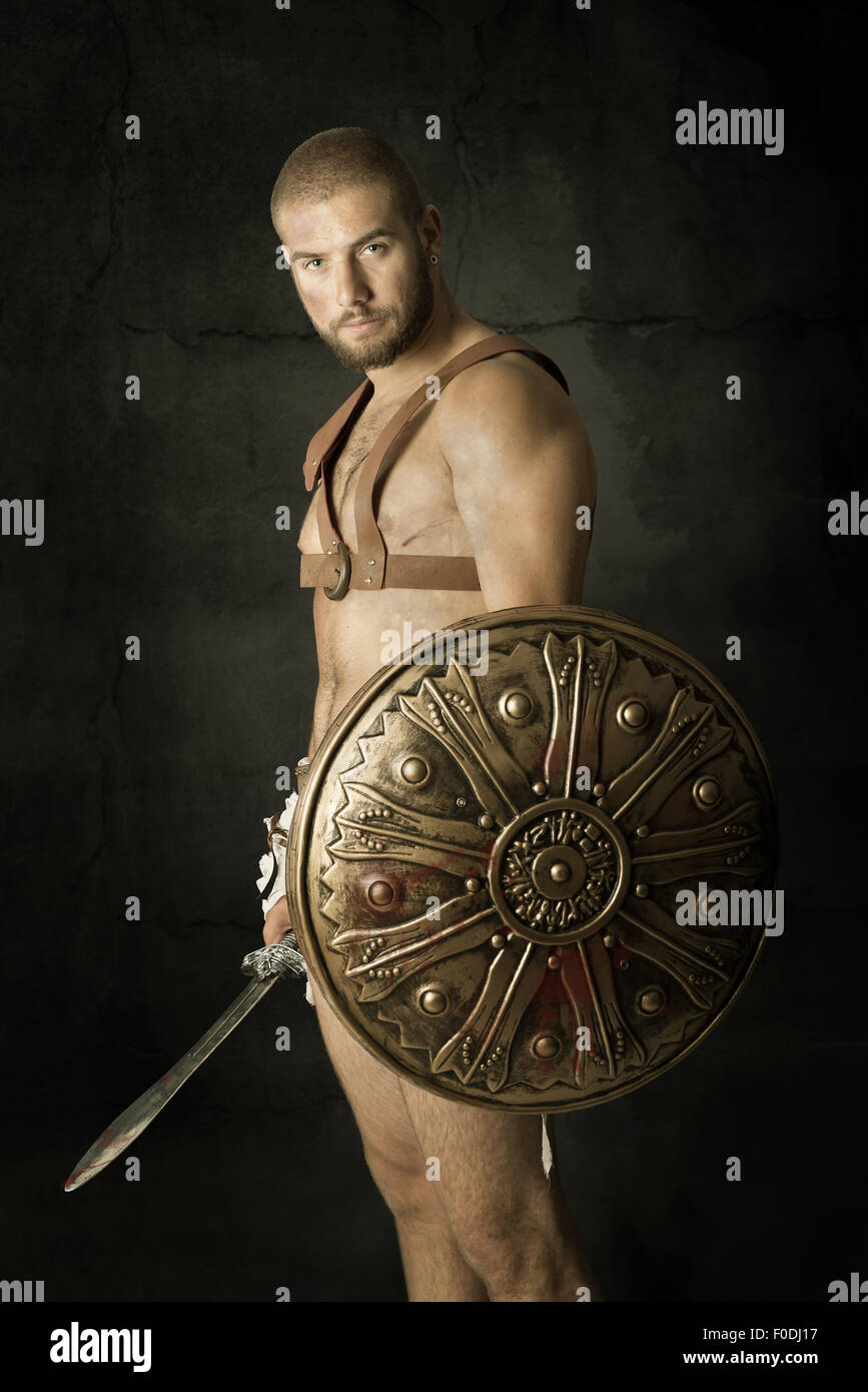 Gladiator posing with shield and sword in a dark background Stock Photo ...