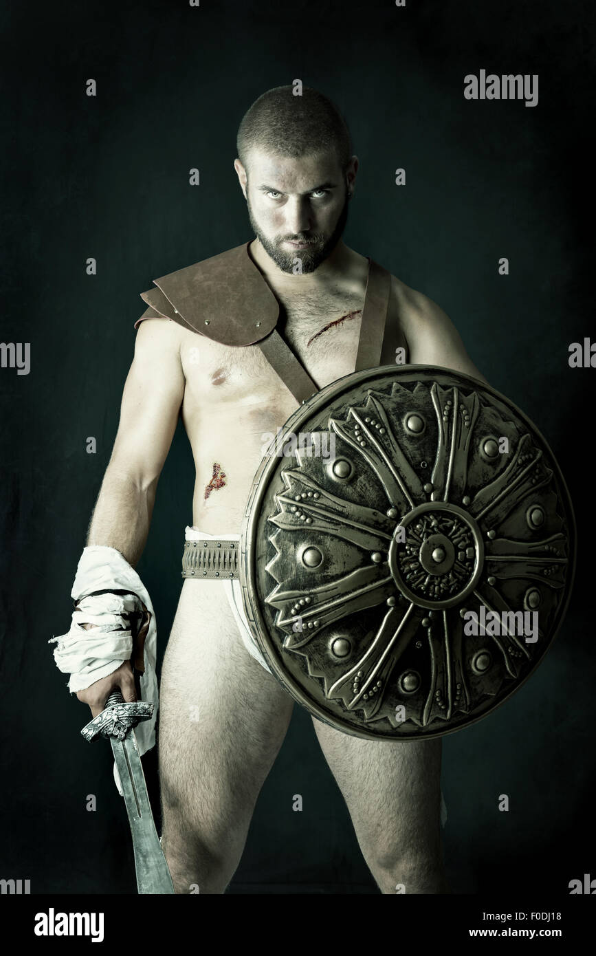 Gladiator posing with shield and sword in a dark background Stock Photo ...