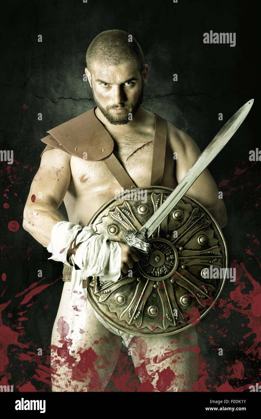 Gladiator posing with shield and sword in a dark background with blood ...