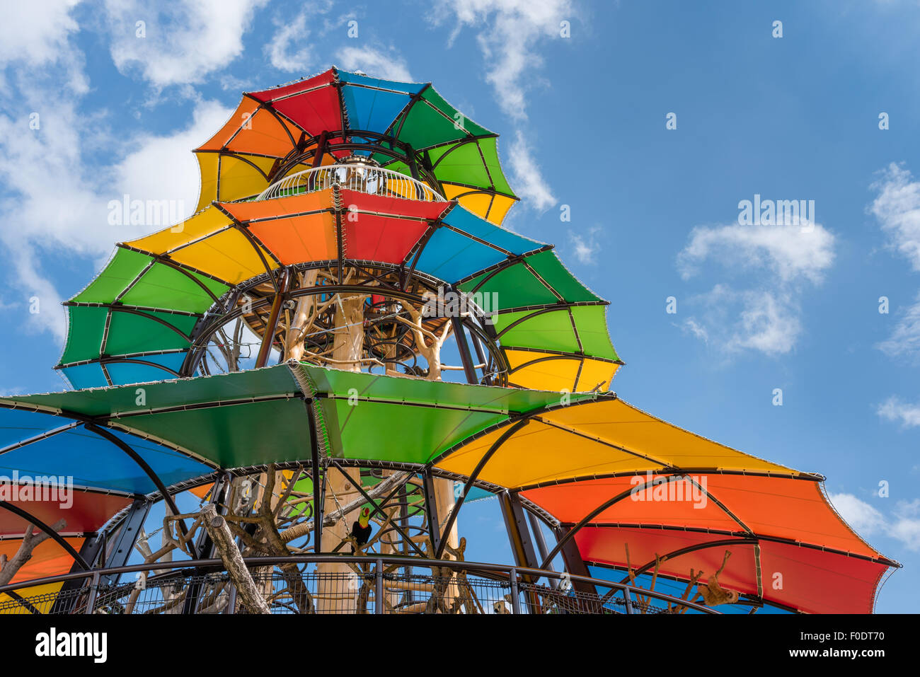 A tall, bright and colorful jungle gym built around some tree trunks on ...