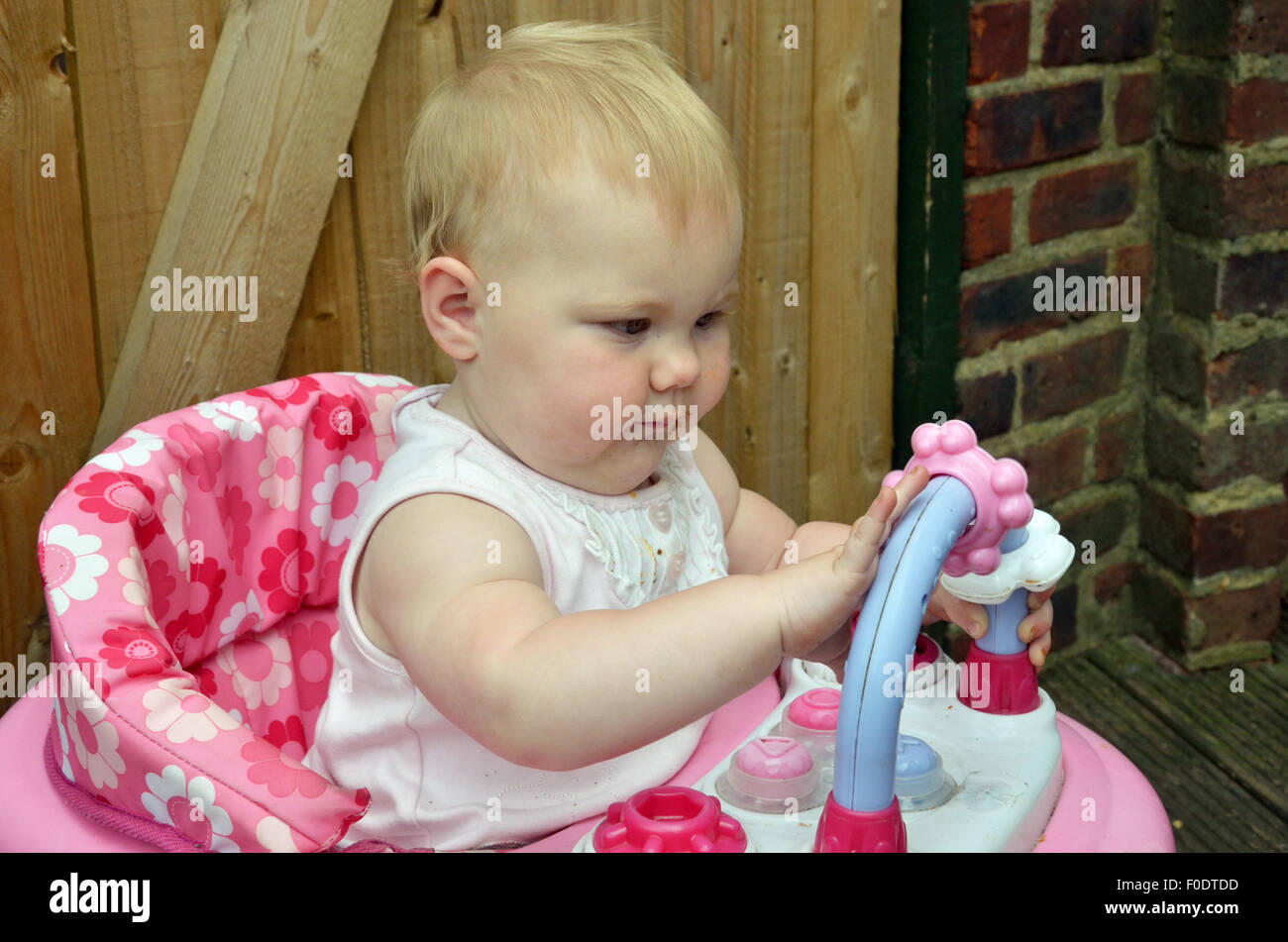 A ten month old baby playing with great concentration out doors on her ...
