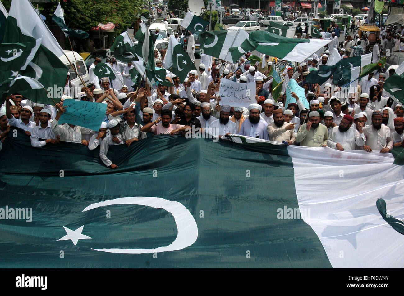 Lahore. 13th Aug, 2015. Pakistani people carry a national flag as they ...