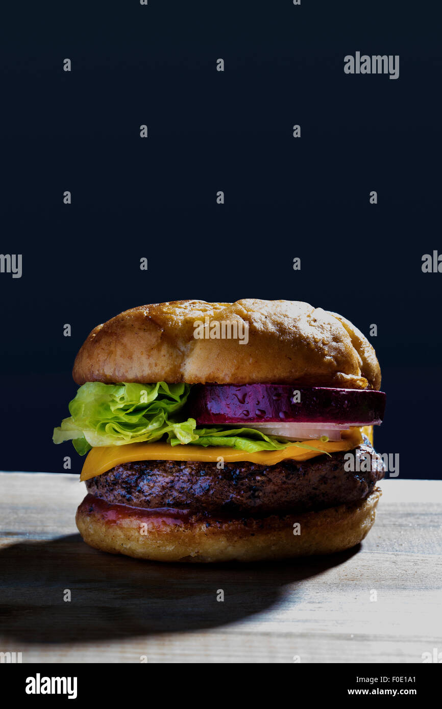 Burger over a wood table and dark background Stock Photo - Alamy