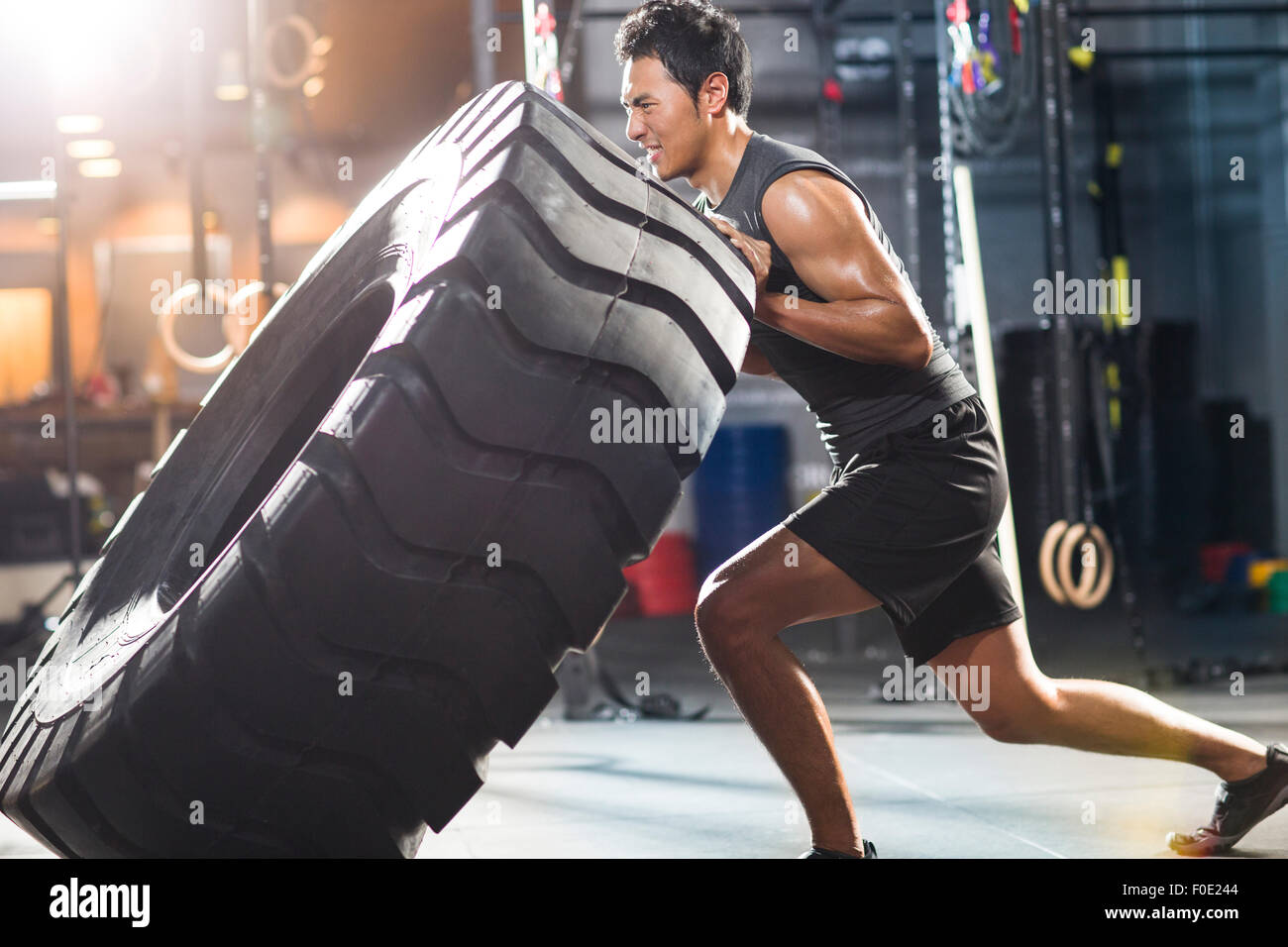 Young man pushing large tire in crossfit gym Stock Photo - Alamy