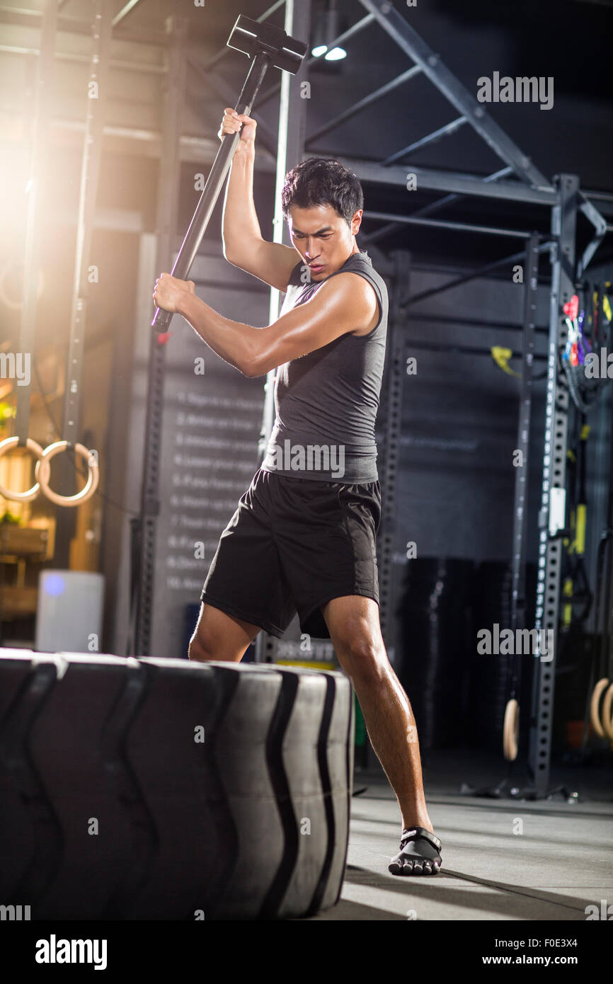 Young man hammering large tire at gym hi-res stock photography and ...