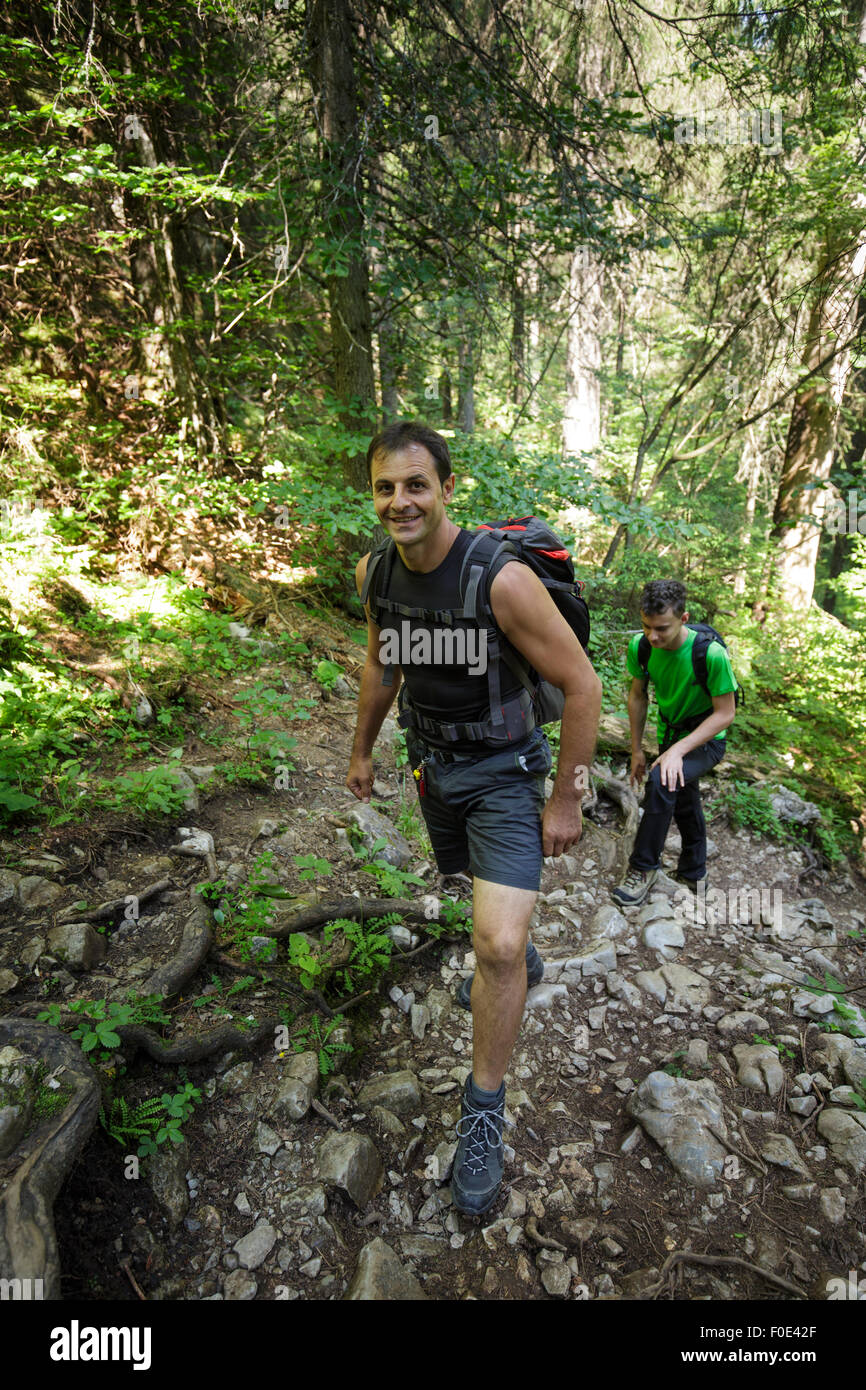 Two hikers with backpacks on a steep trail in the forest Stock Photo ...