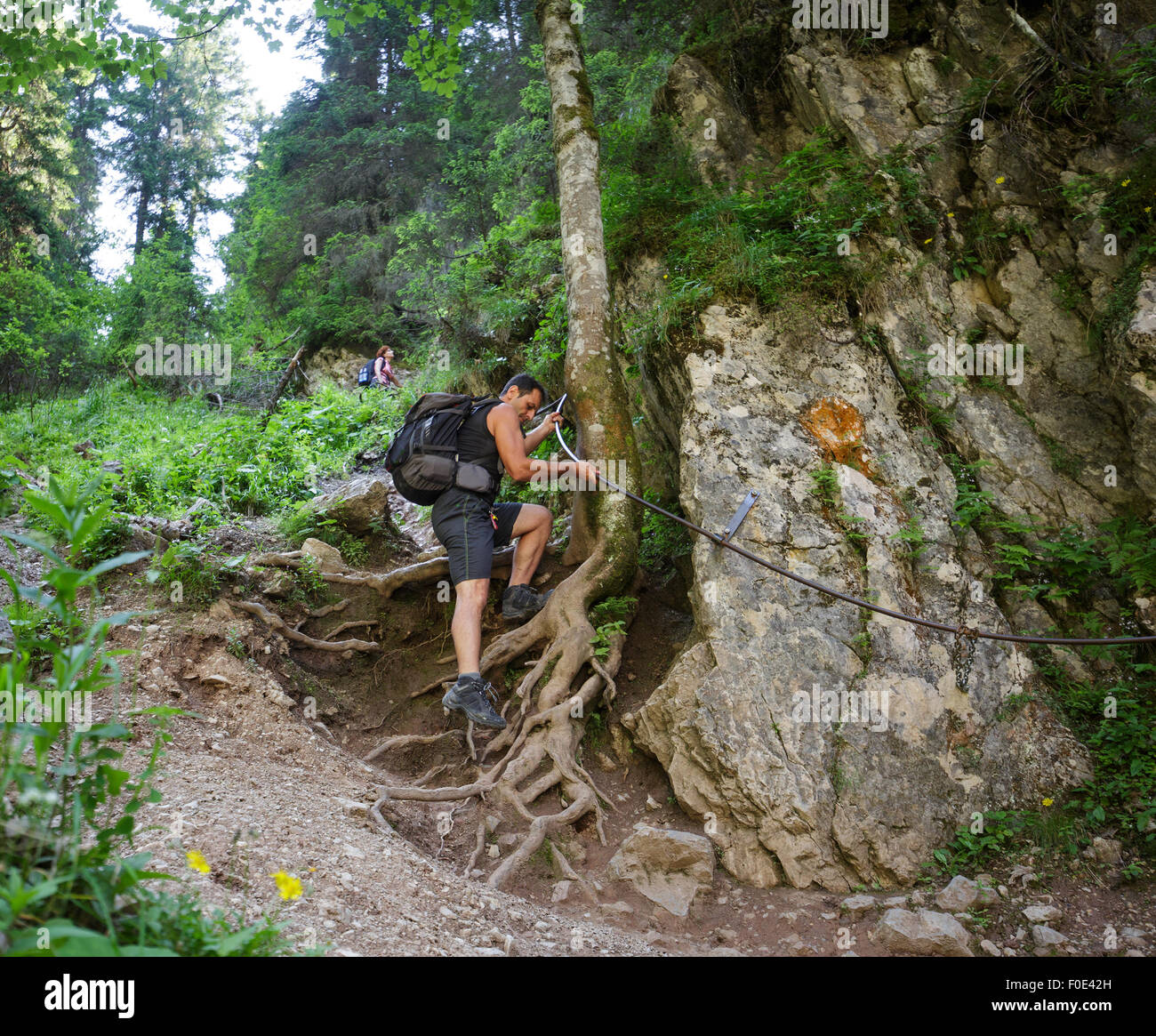 Family of hikers climbing on a safety cable on a very steep trail Stock ...