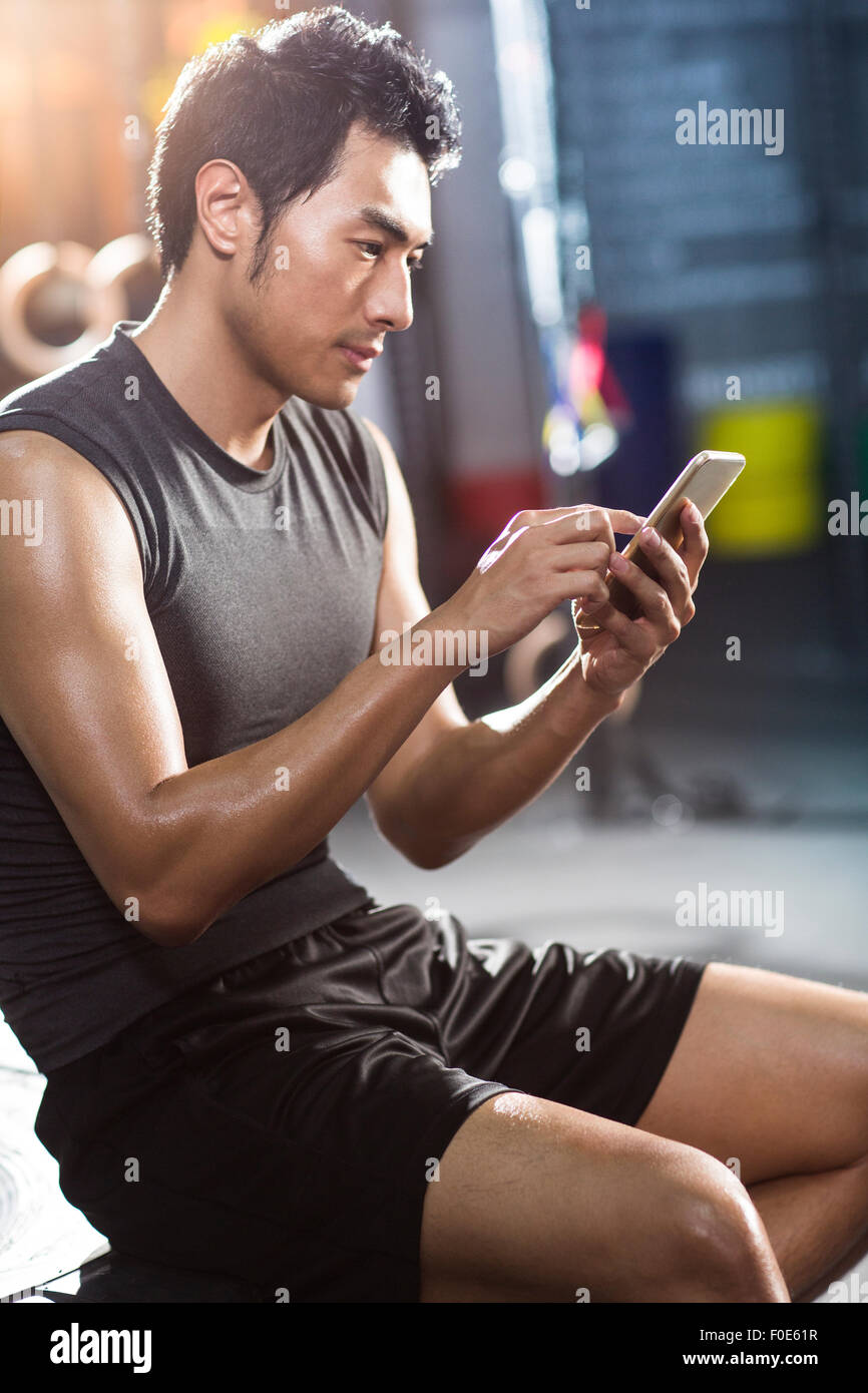 Young man using smart phone in gym Stock Photo - Alamy