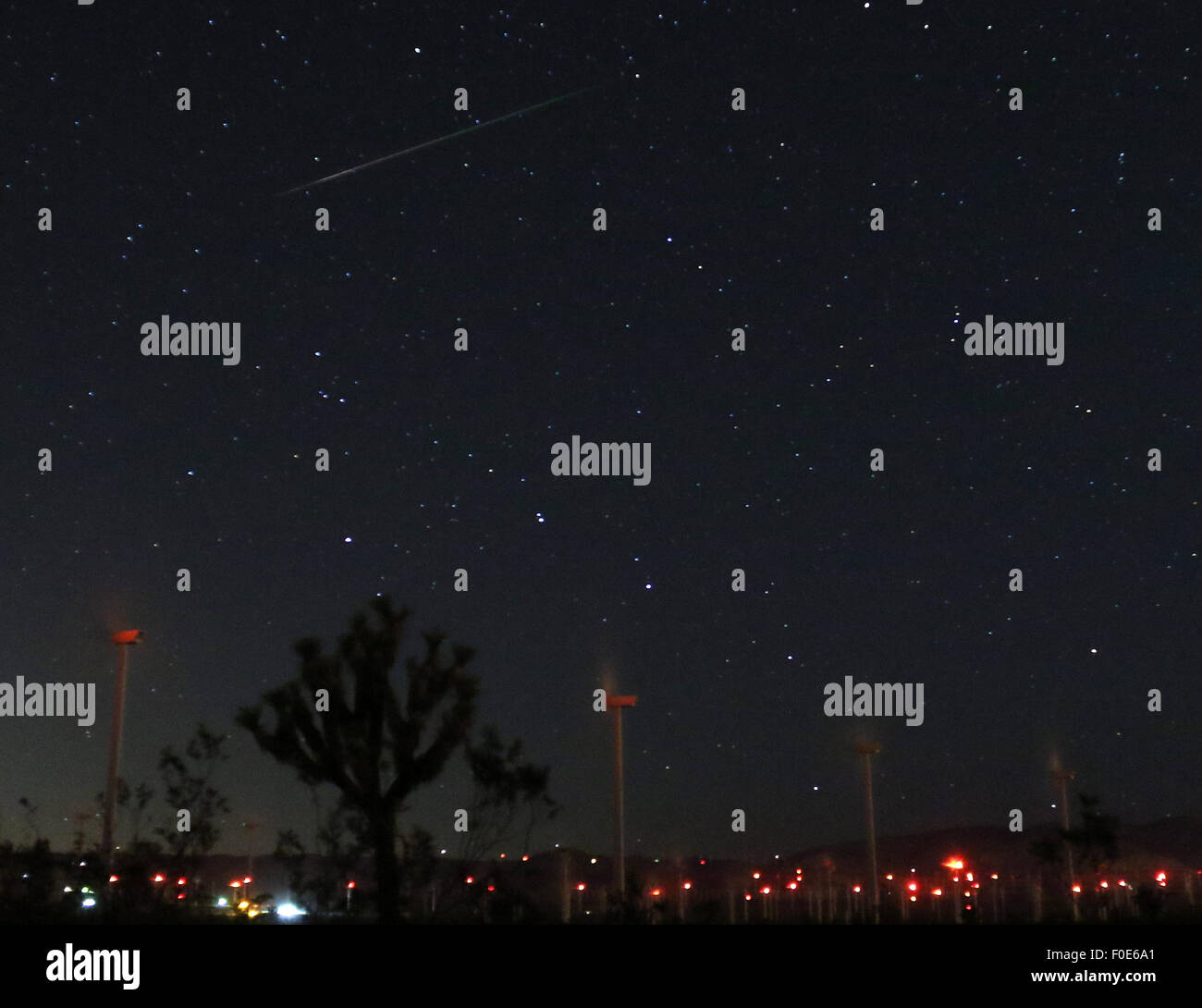 Meteors shoot across the night skies over a wind mill farm during the ...