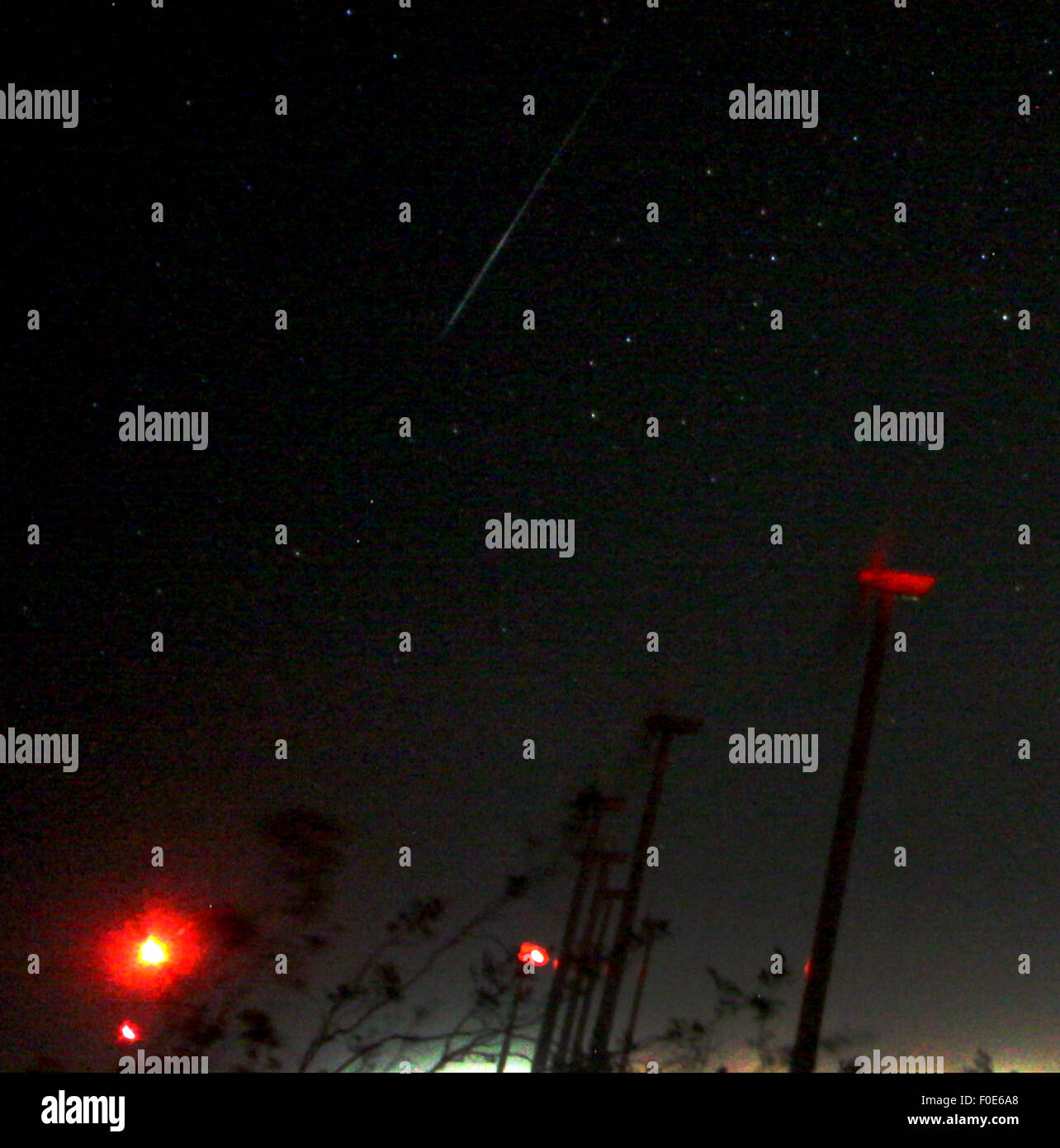 Meteors shoot across the night skies over a wind mill farm during the ...