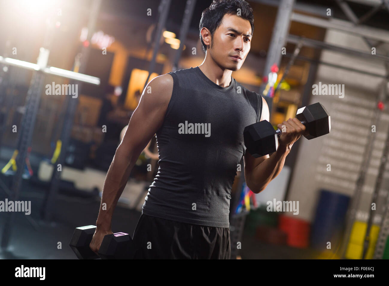 Young man lifting weights at gym Stock Photo - Alamy