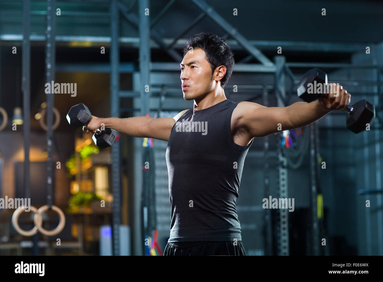 Young man lifting weights at gym Stock Photo - Alamy