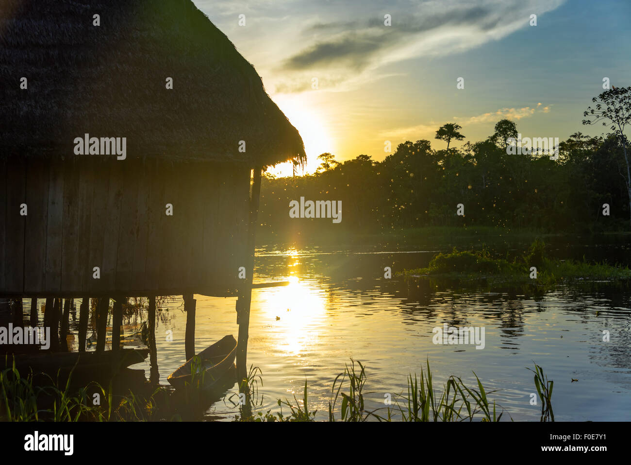 Silhouette of a shack on stilts at sunset in a village near Iquitos ...
