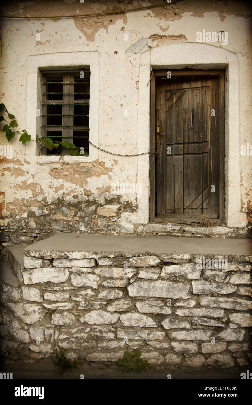Abandoned house's door locked with an rusty old chain thru the window ...