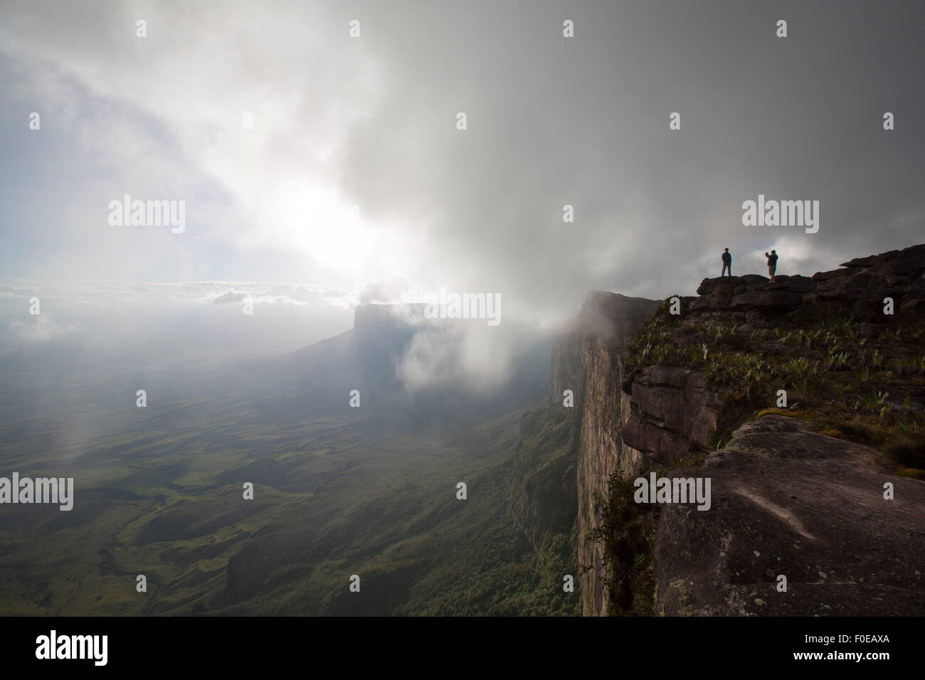 Two people taking photos at the top of Mount Roraima in the clouds. The ...