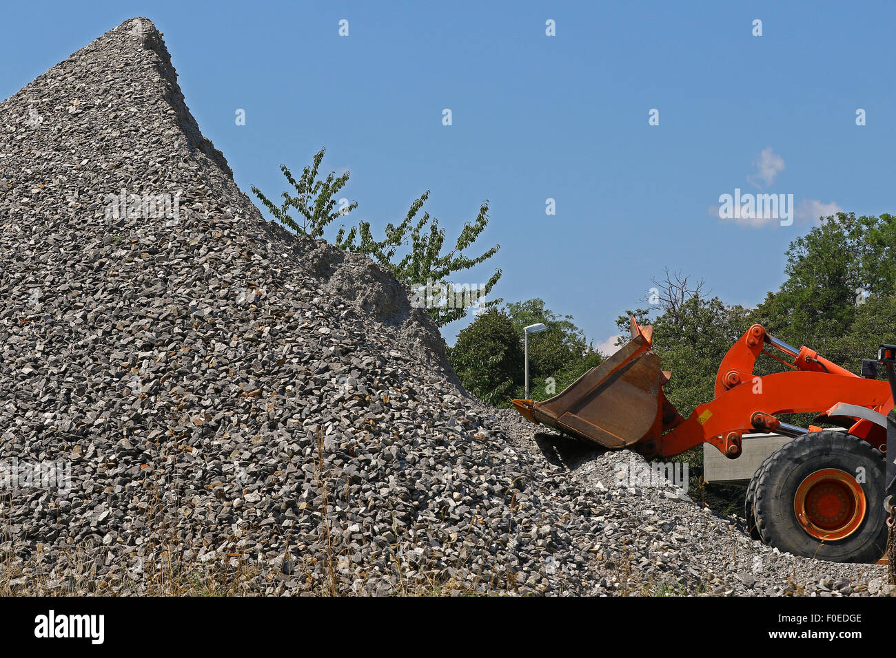 Excavator in front of a pile of rubble outside a mine against blue ...